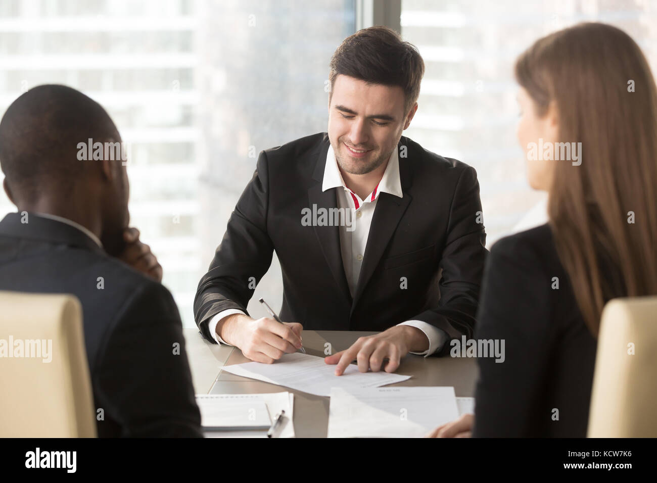 Smiling caucasian businessman singing contract during negotiation with ...