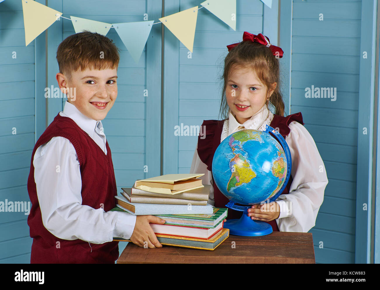 Portrait of smiling school kids doing homework in library at schoolk ...
