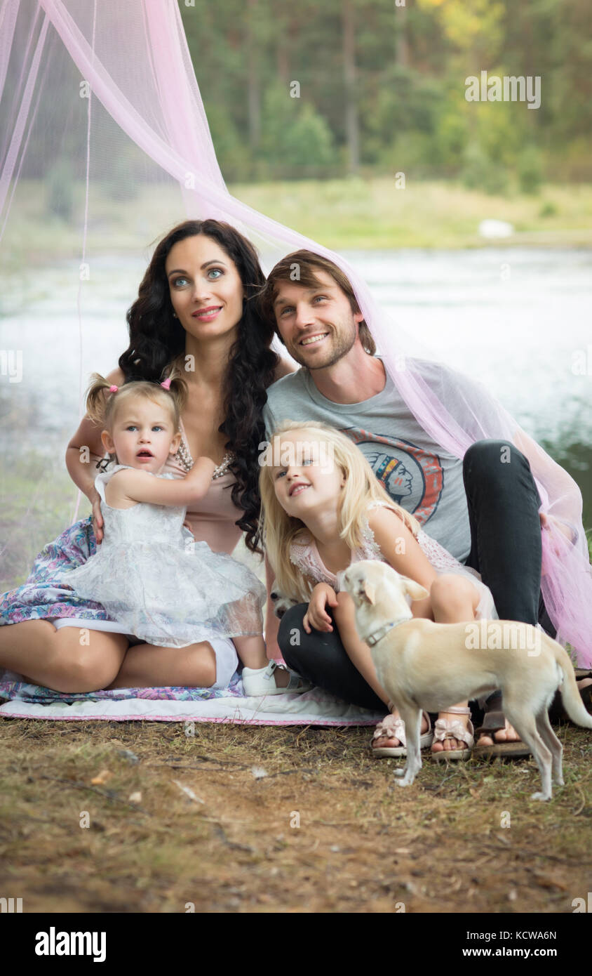 Beautiful young family with two daughters walking in the forest in ...