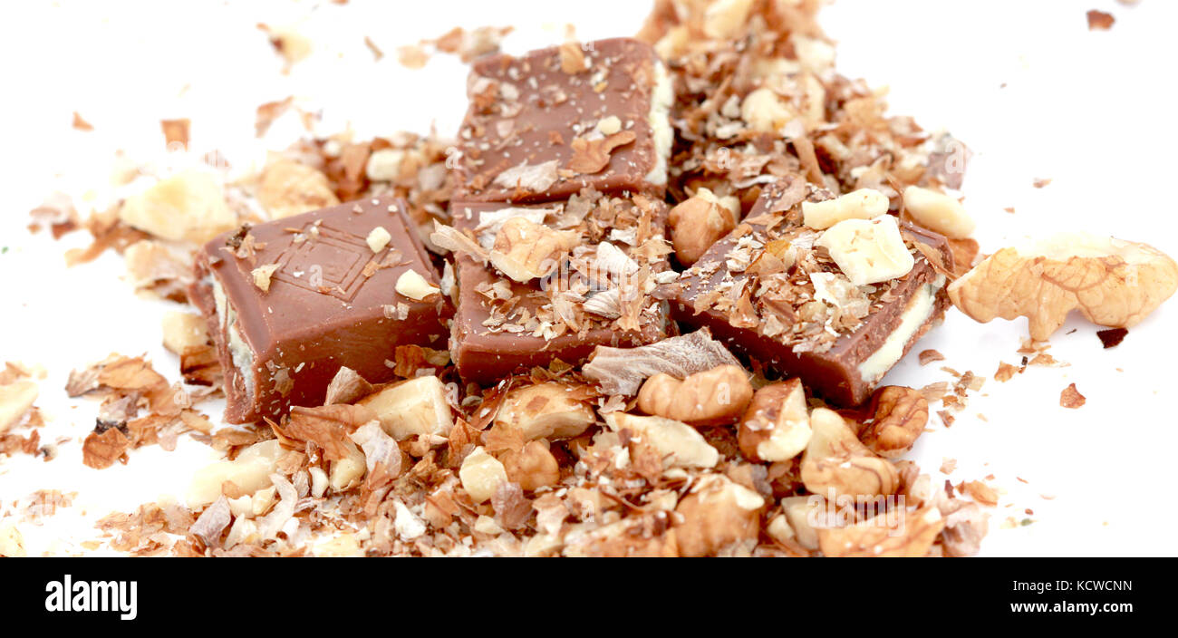 close up a stuffed chocolate bar and walnut pieces on white background ...