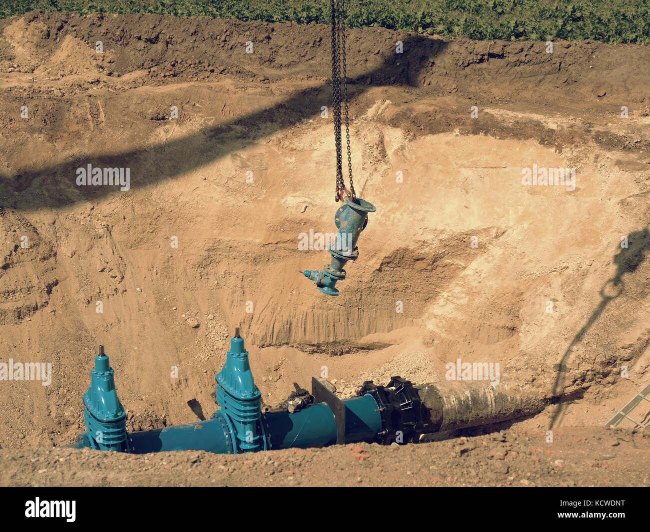 Crane lifting tube and gate valve within water pipeline building. New ...