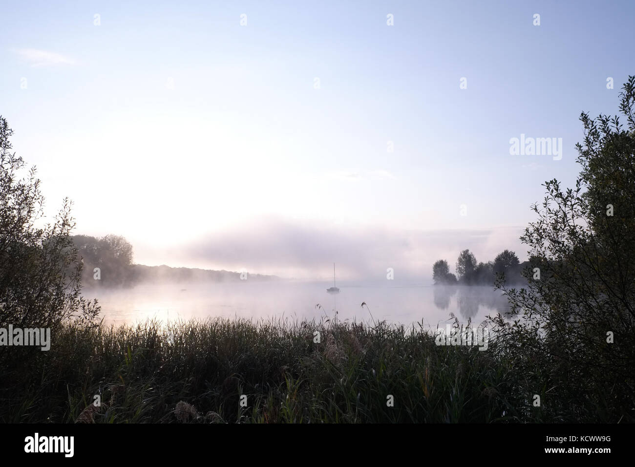 Morning mist over lake with sailboat - 1 Stock Photo - Alamy