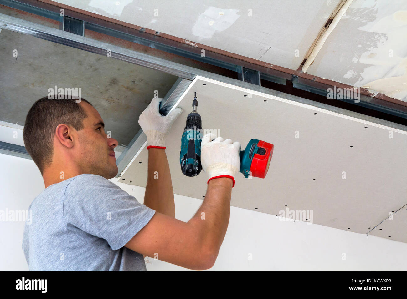 Construction worker assemble a suspended ceiling with drywall and ...