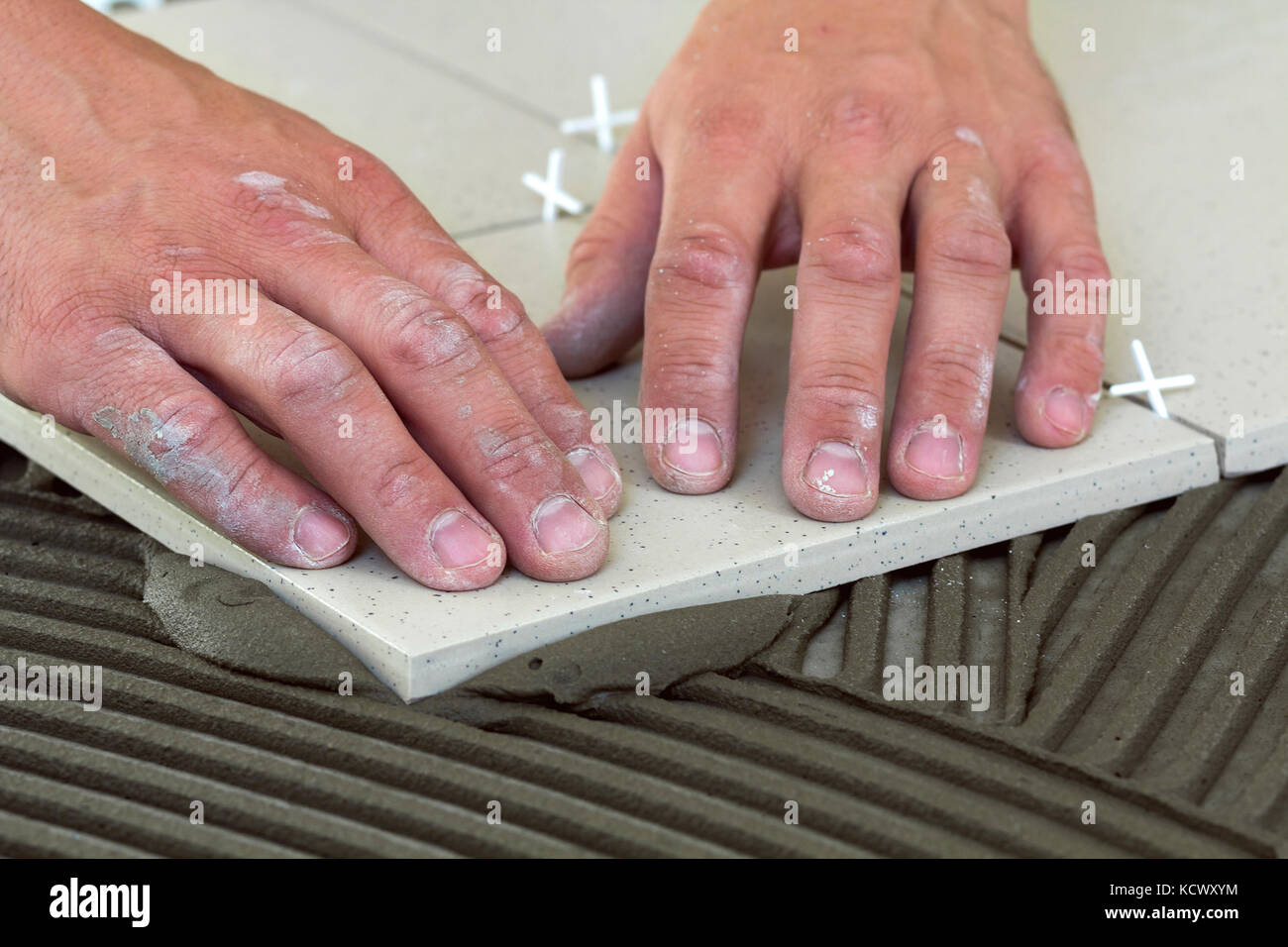 Workers hands with ceramic tiles and tools for tiler. Floor tiles ...