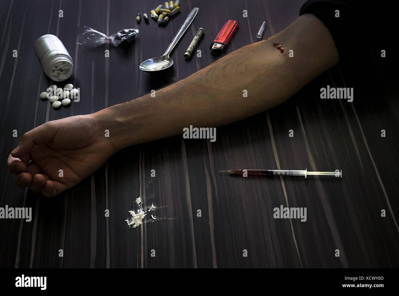 The hand of a drug addict lying beside on the table beside the syringe ...