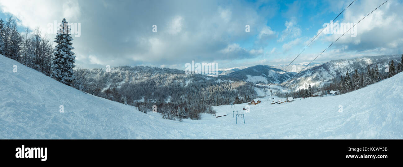 The first shadows of setting sun on winter mountain slopes with ski run ...