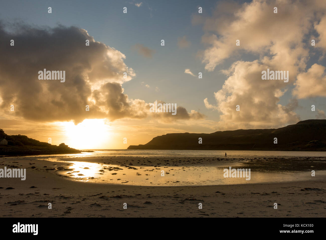 Lone person walking along Calgary Bay beach at sunset and low tide ...