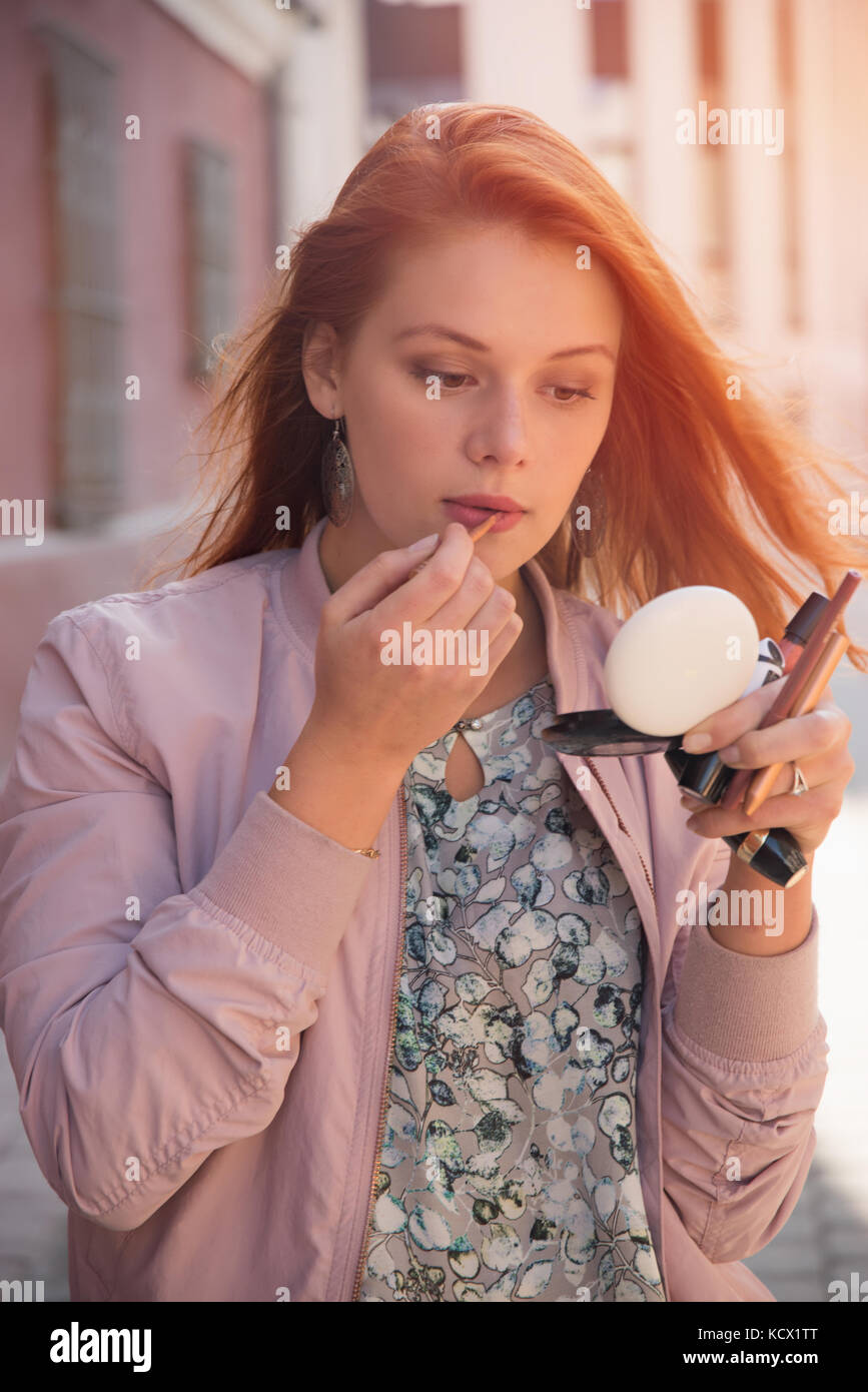 girl doing makeup on the street. Colour lips Stock Photo - Alamy