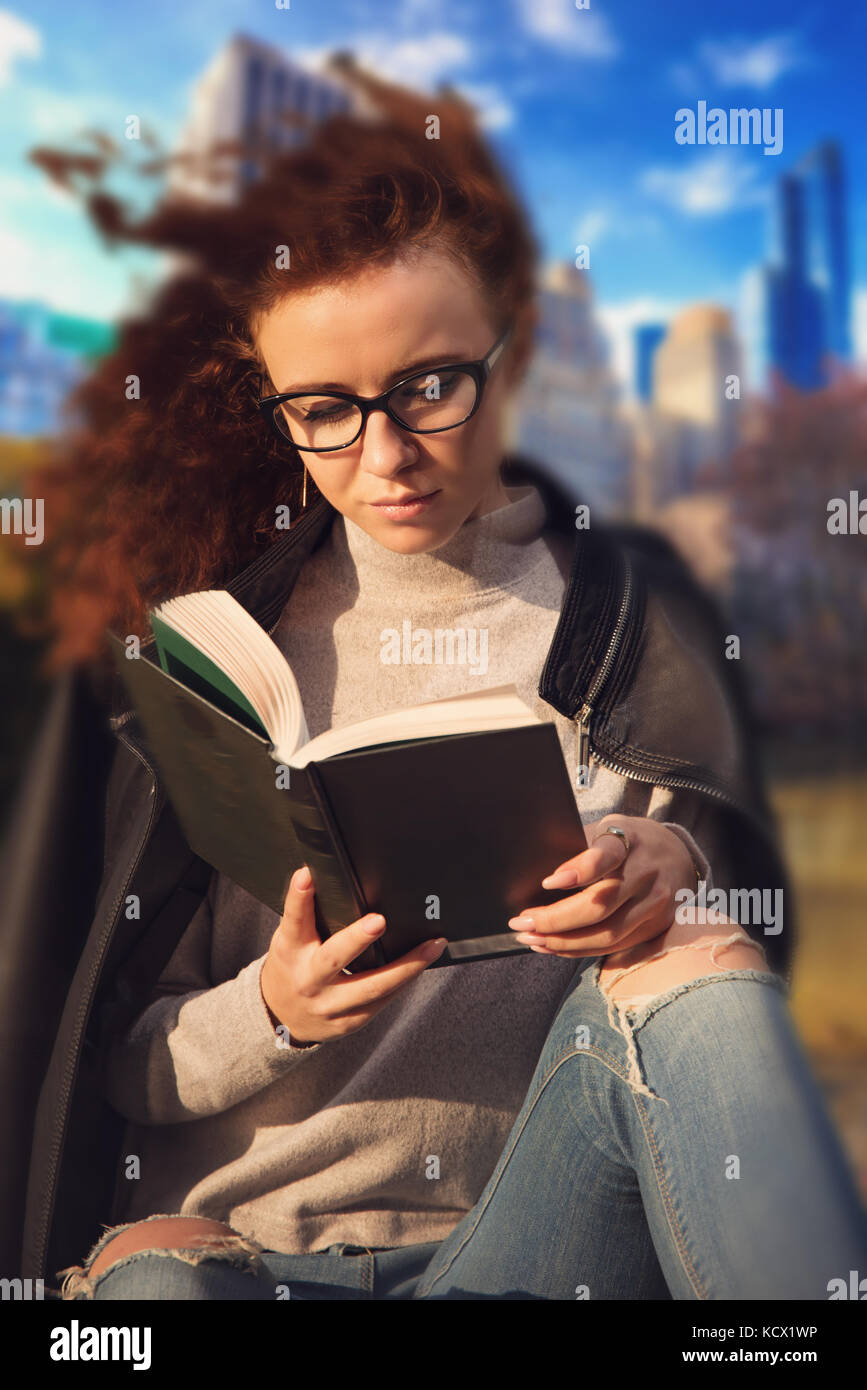 girl with red hair reading a book in central park Manhattan New York ...