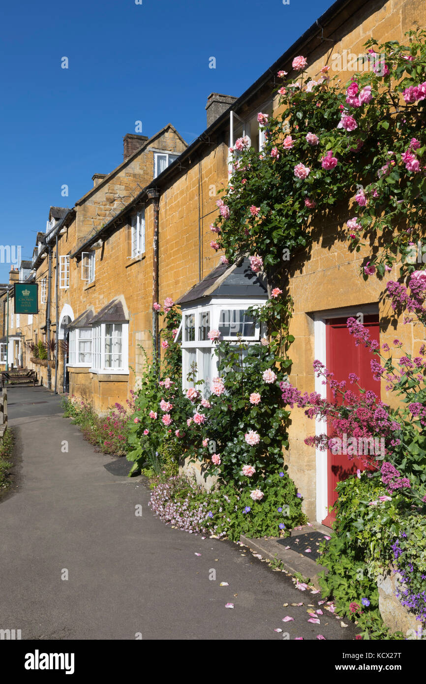 Rose covered frontage of Cotswold stone cottages along High Street ...