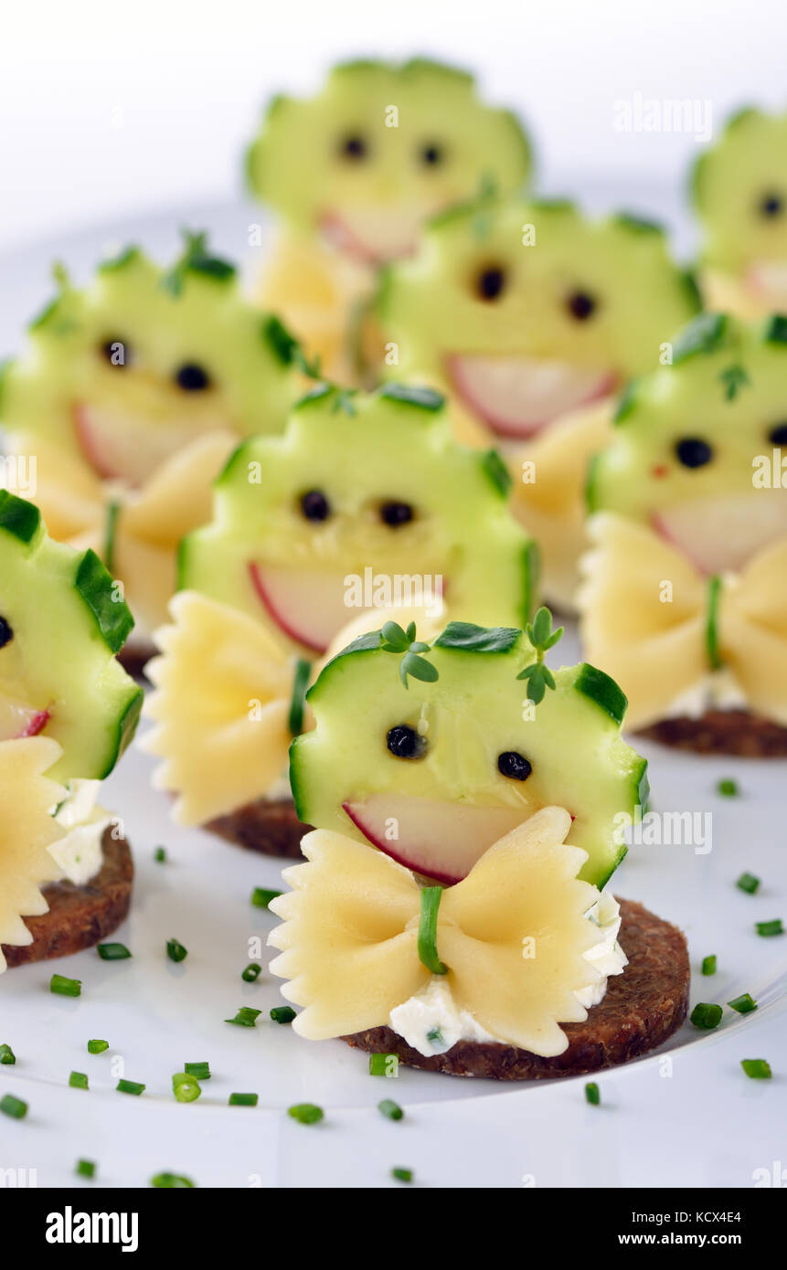 Funny snacks with spicy cream cheese, decorated with cucumber, radishes ...