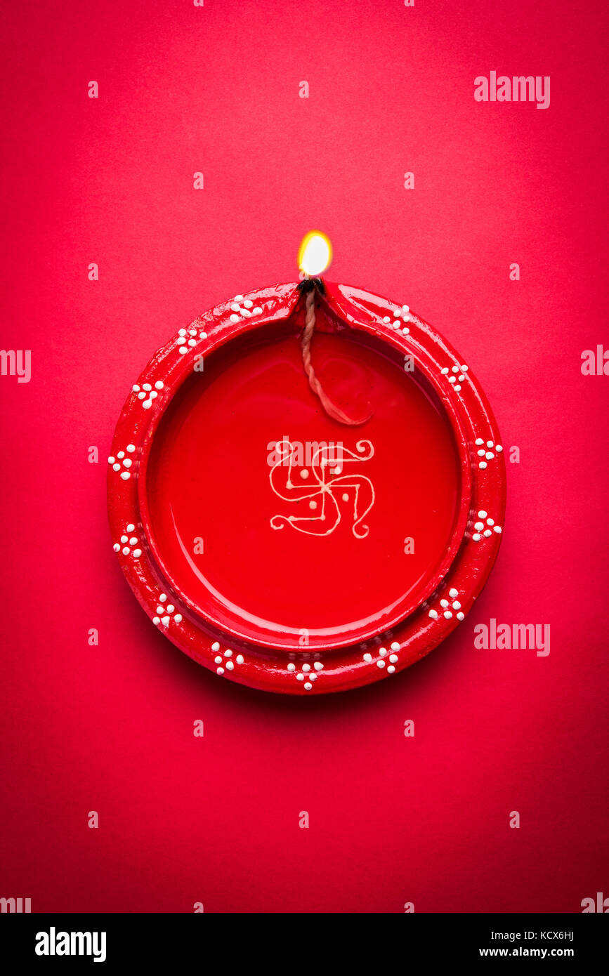 Big illuminated diwali diya or clay lamp placed over satin cloth ...