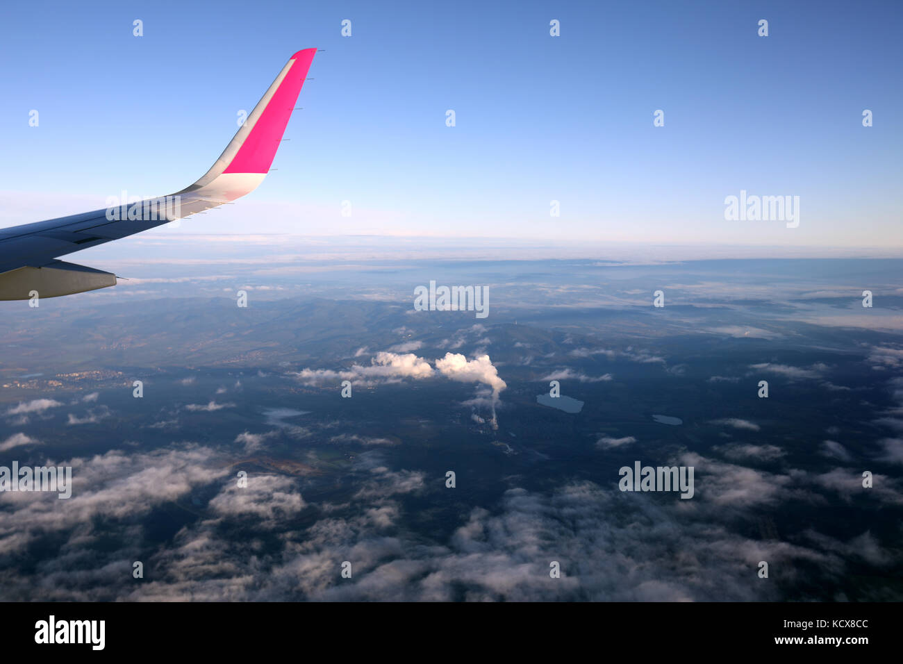 View of window at flying airplane and sky with clouds from top view ...