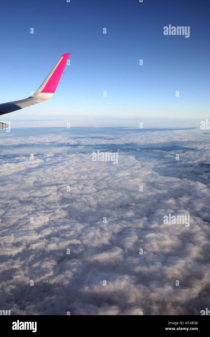 View of window at flying airplane and sky with clouds from top view ...