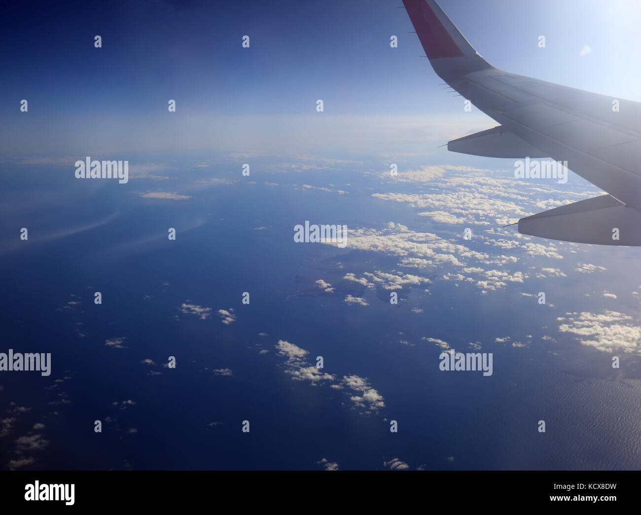 View of window at flying airplane and sky with clouds from top view ...
