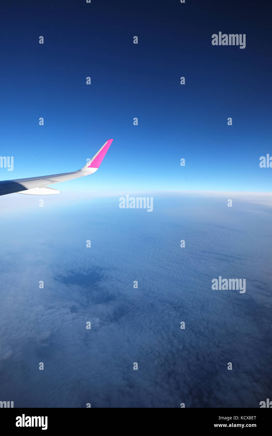 View of window at flying airplane and sky with clouds from top view ...