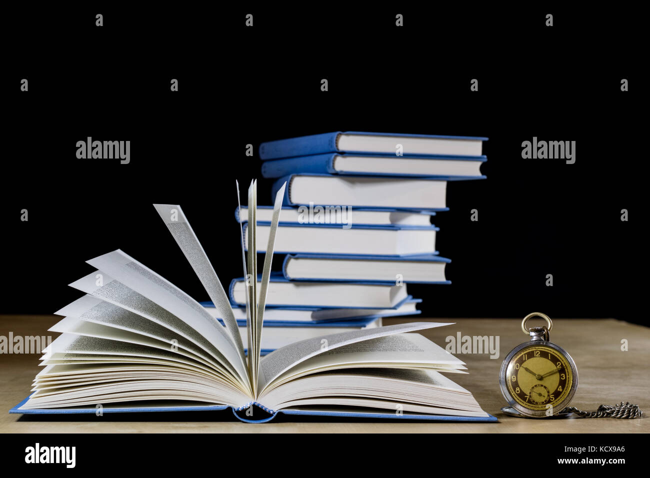 Heap of books reading on a wooden table. Beside lies and watch. Black ...
