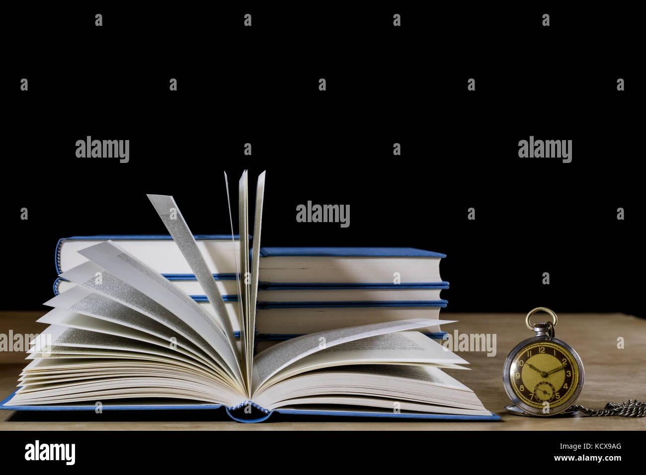 Heap of books reading on a wooden table. Beside lies . Black background ...