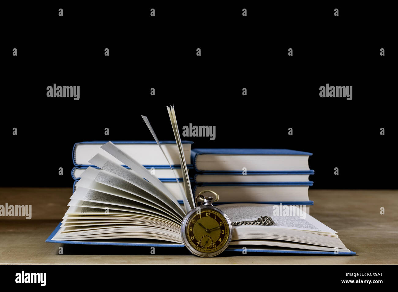 Heap of books reading on a wooden table. Beside lies . Black background ...