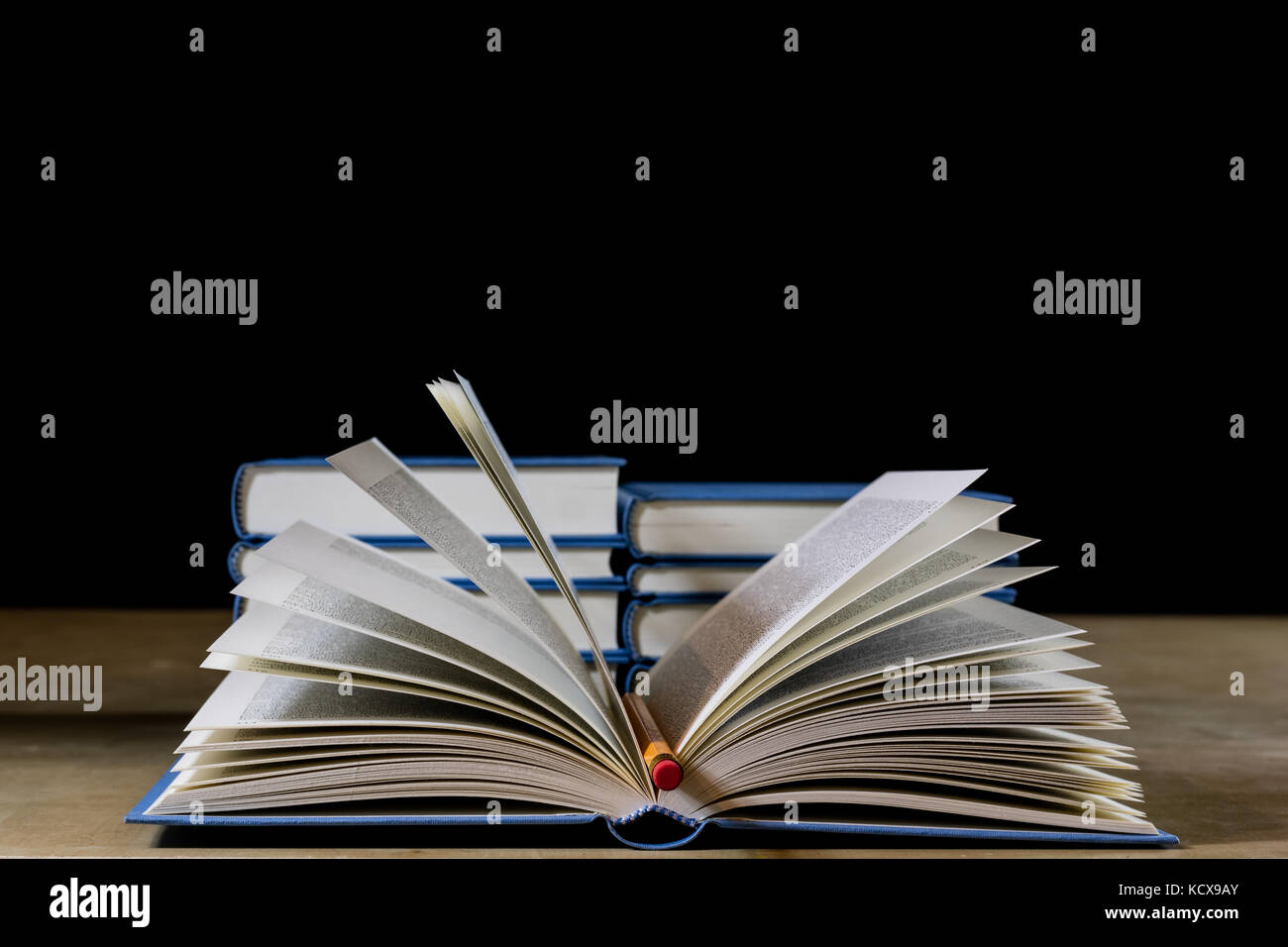 Heap of books reading on a wooden table. Beside lies . Black background ...