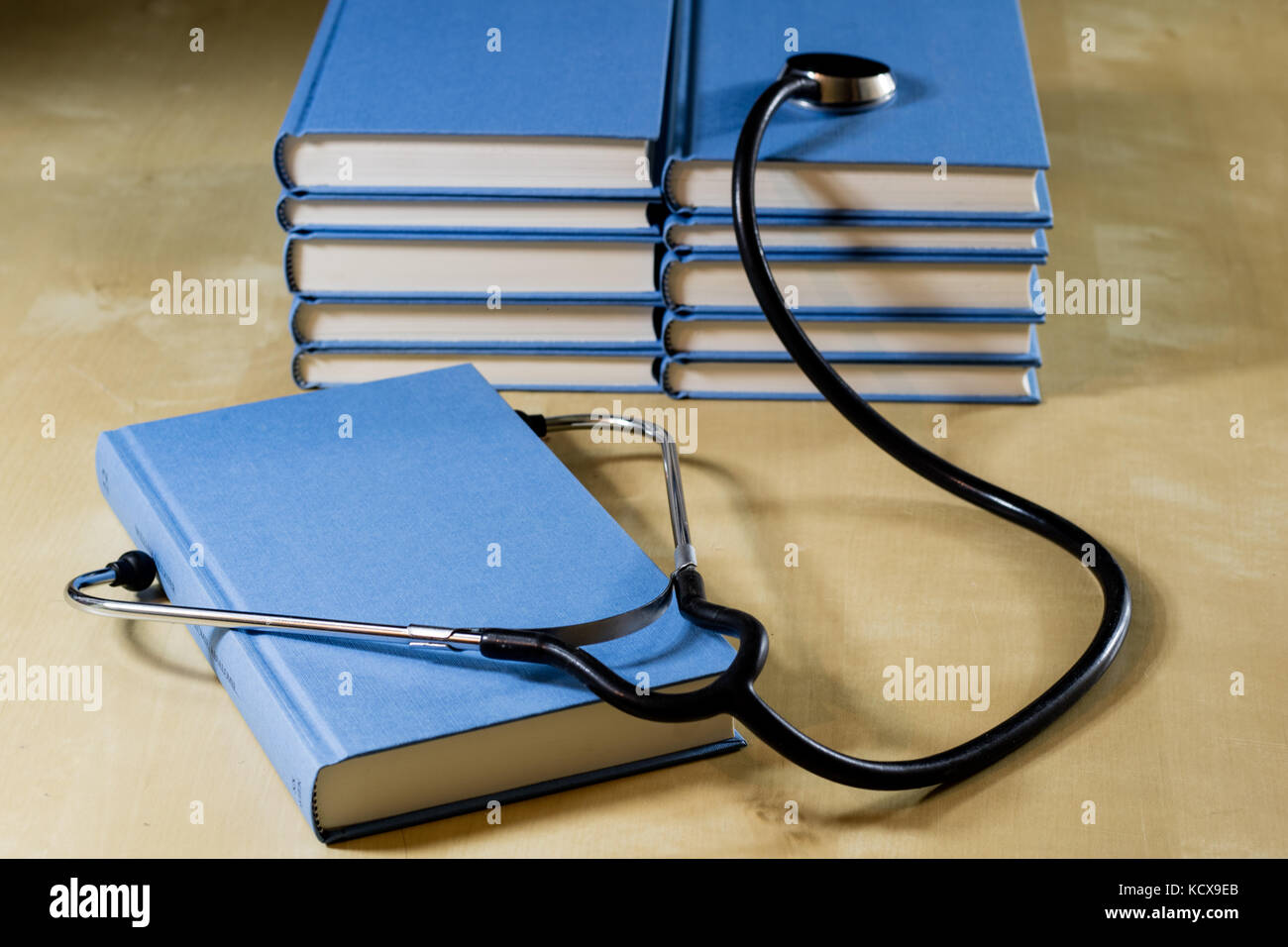Heap of books reading on a wooden table. Beside lies and stethoscope ...