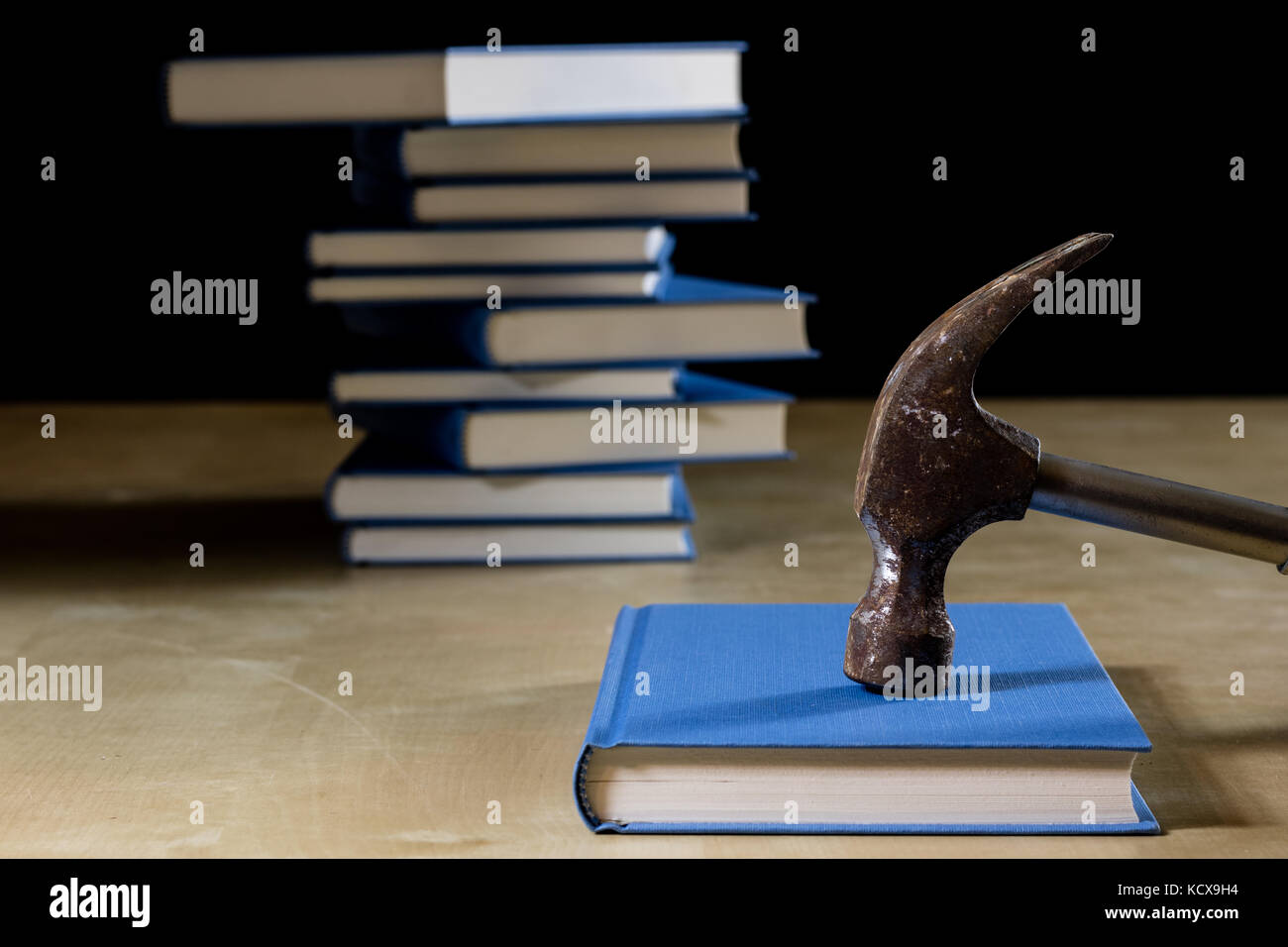 Heap of books reading on a wooden table. Beside lies and hammer. Black ...