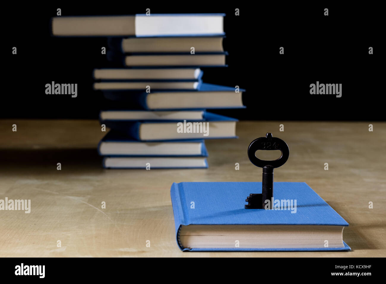 Heap of books reading on a wooden table. Beside lies and key. Black ...