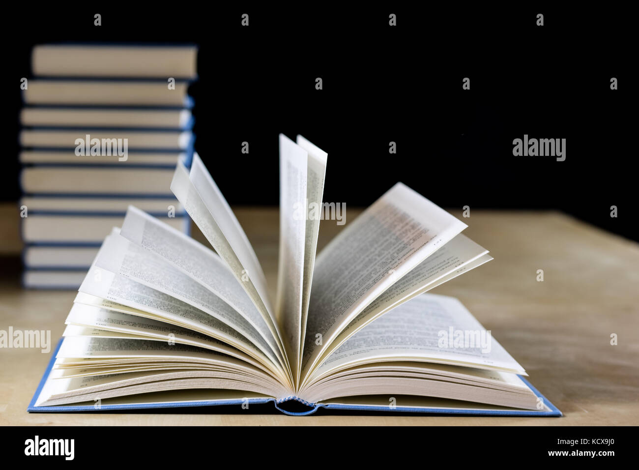 Heap of books reading on a wooden table. Beside lies . Black background ...