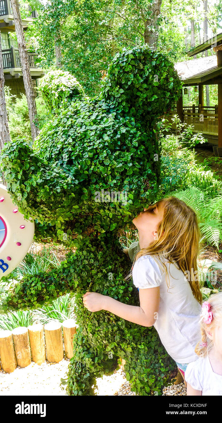 Child hugging a grass bush art of Mickey Mouse, Disney World Florida ...