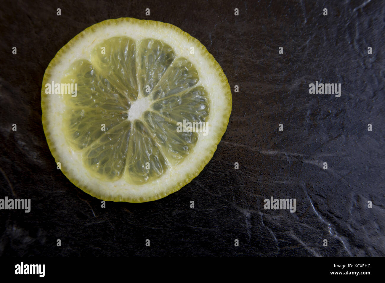 Thin slice of lemon on black marble with copy space Stock Photo - Alamy