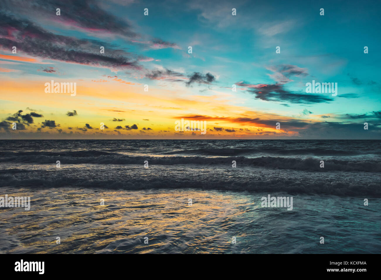 first light over the ocean creating a colorful sky just before sunrise ...