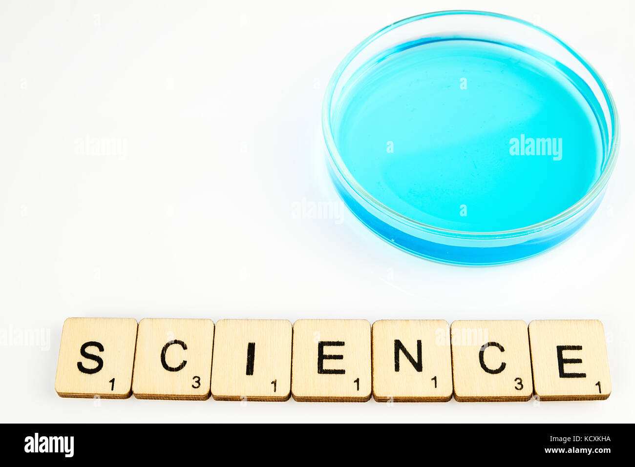 word science written in letter tiles with a petri dish of blue copper ...