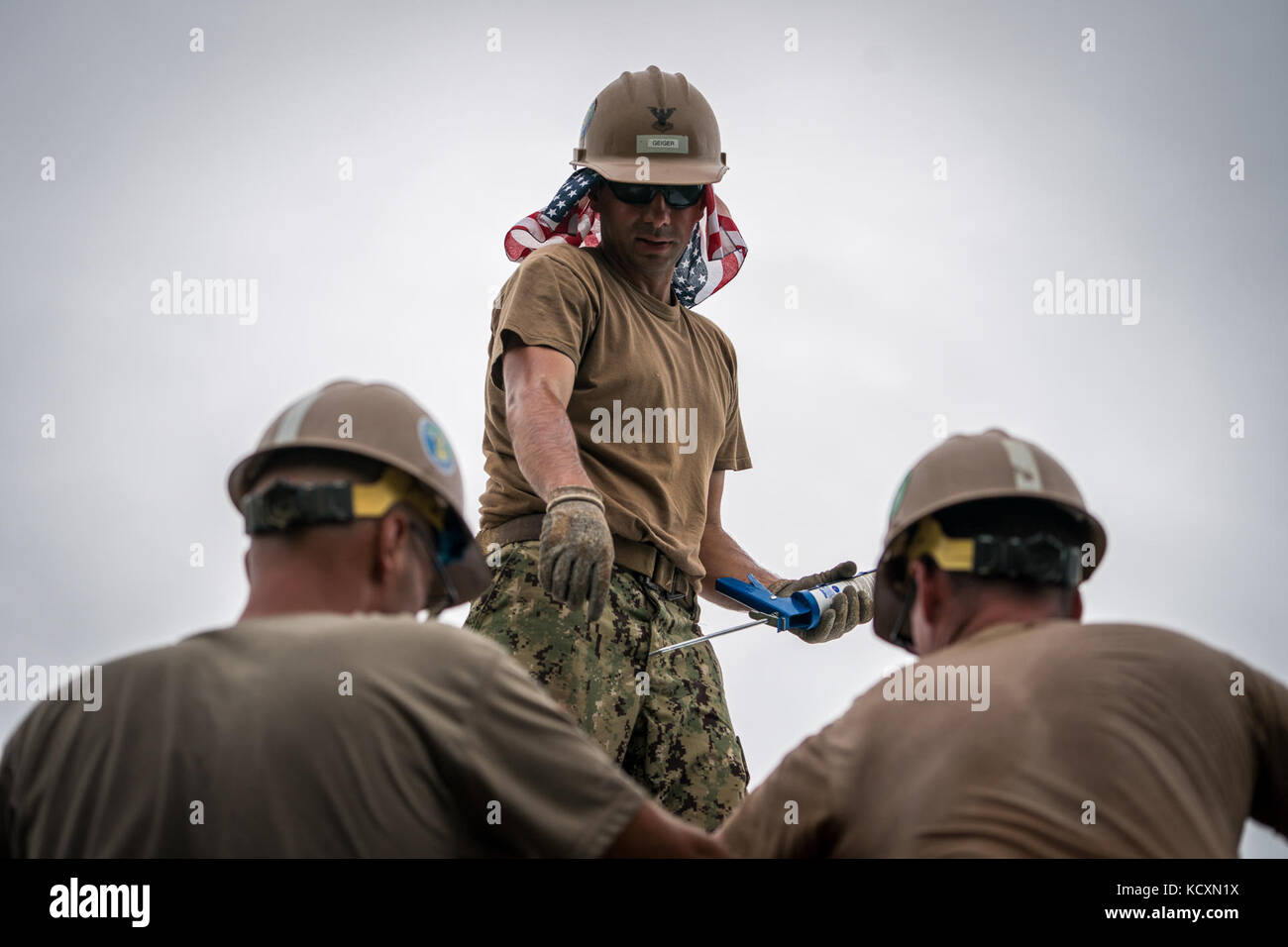 U.S. Navy BU2 Kevin Geiger asks his fellow seabees to hand him a tool ...
