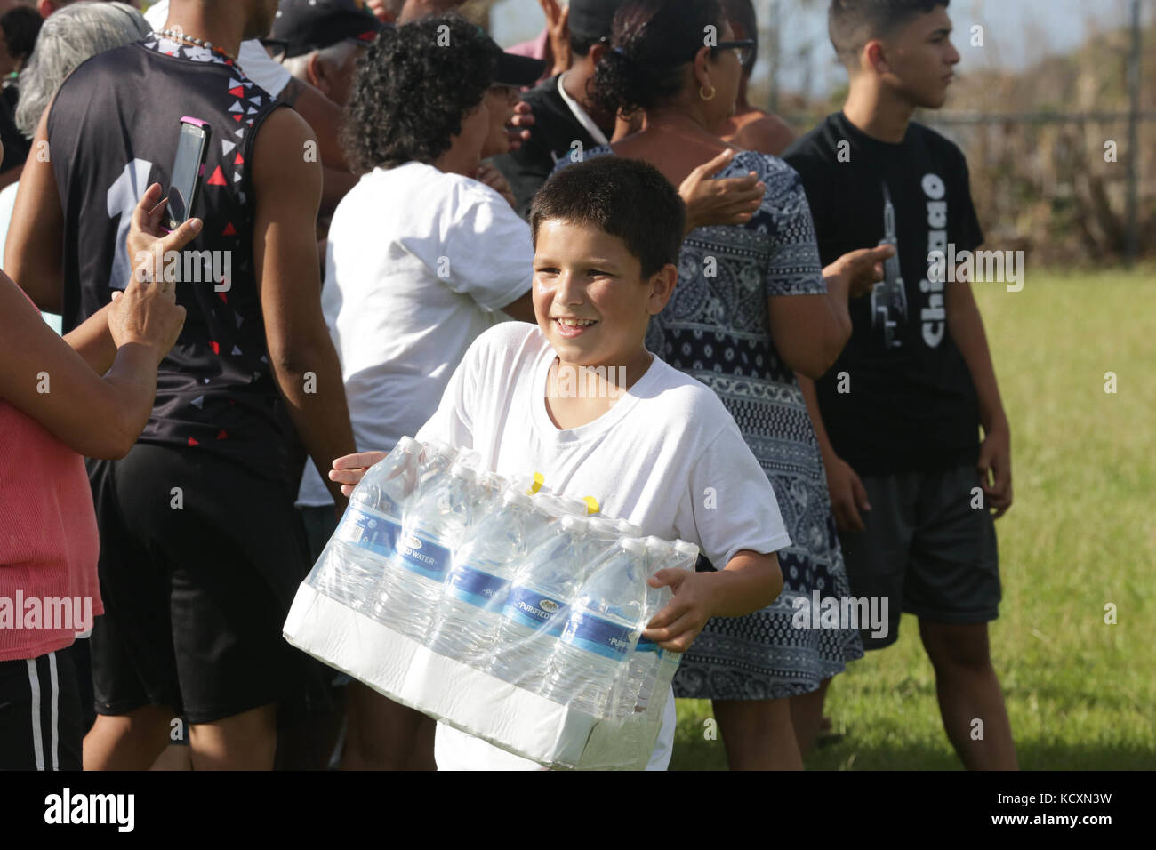 A Puerto Rican boy carries a case of water delivered by the U.S. Army ...