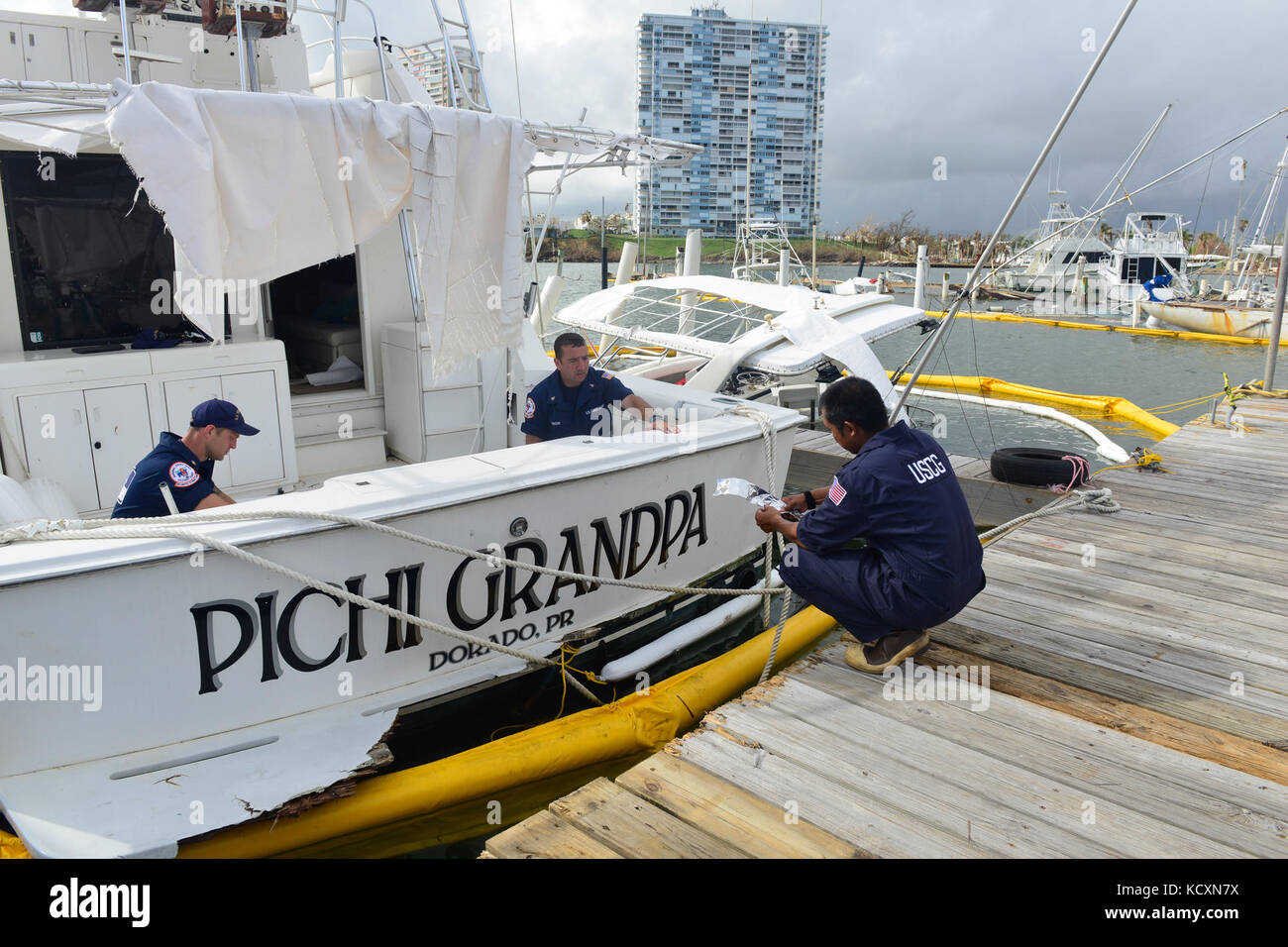 Coast Guard members assess damage to a vessel at a marina in the wake ...