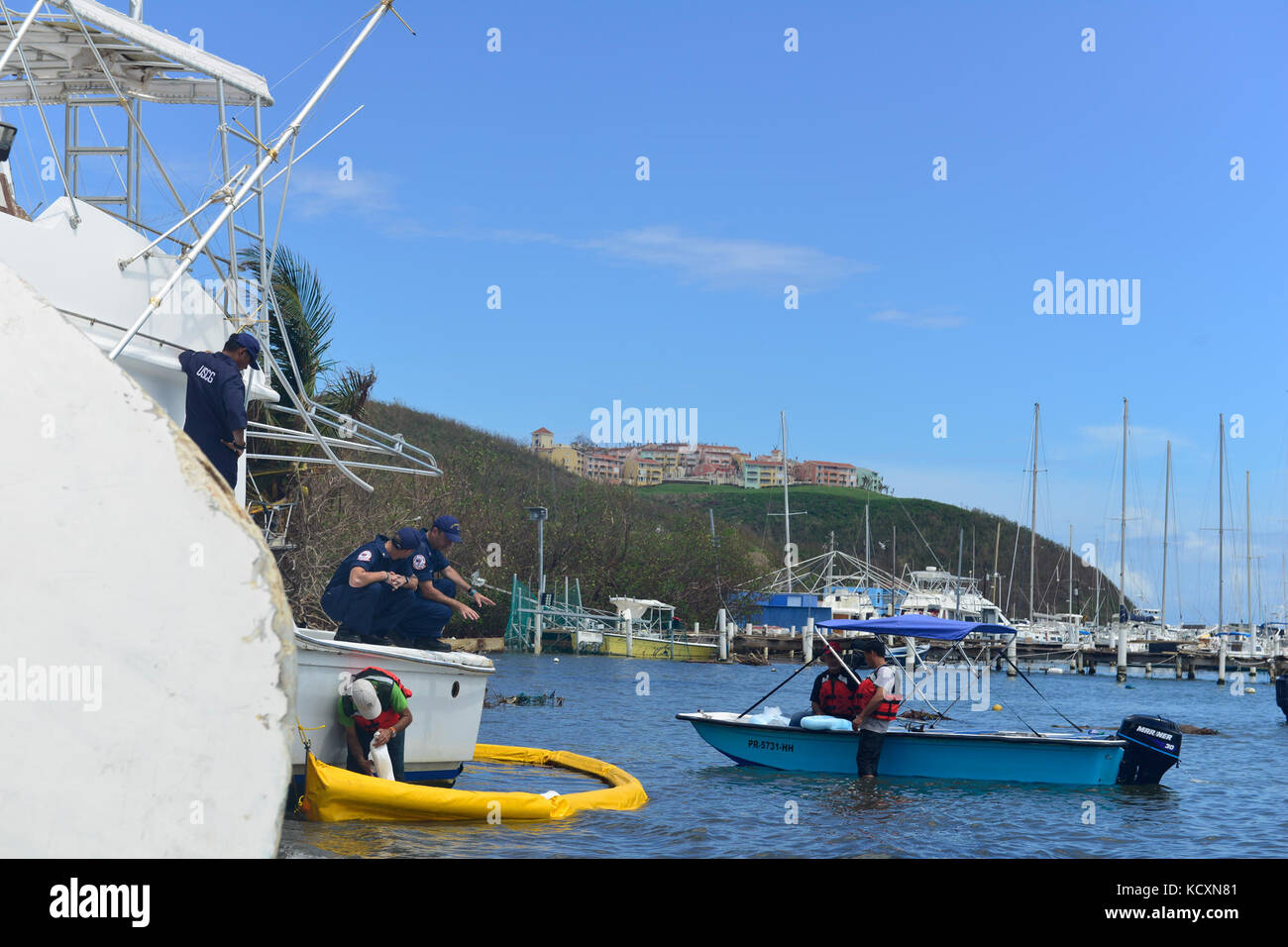 Coast Guard members and contractors place boom around a vessel at a ...