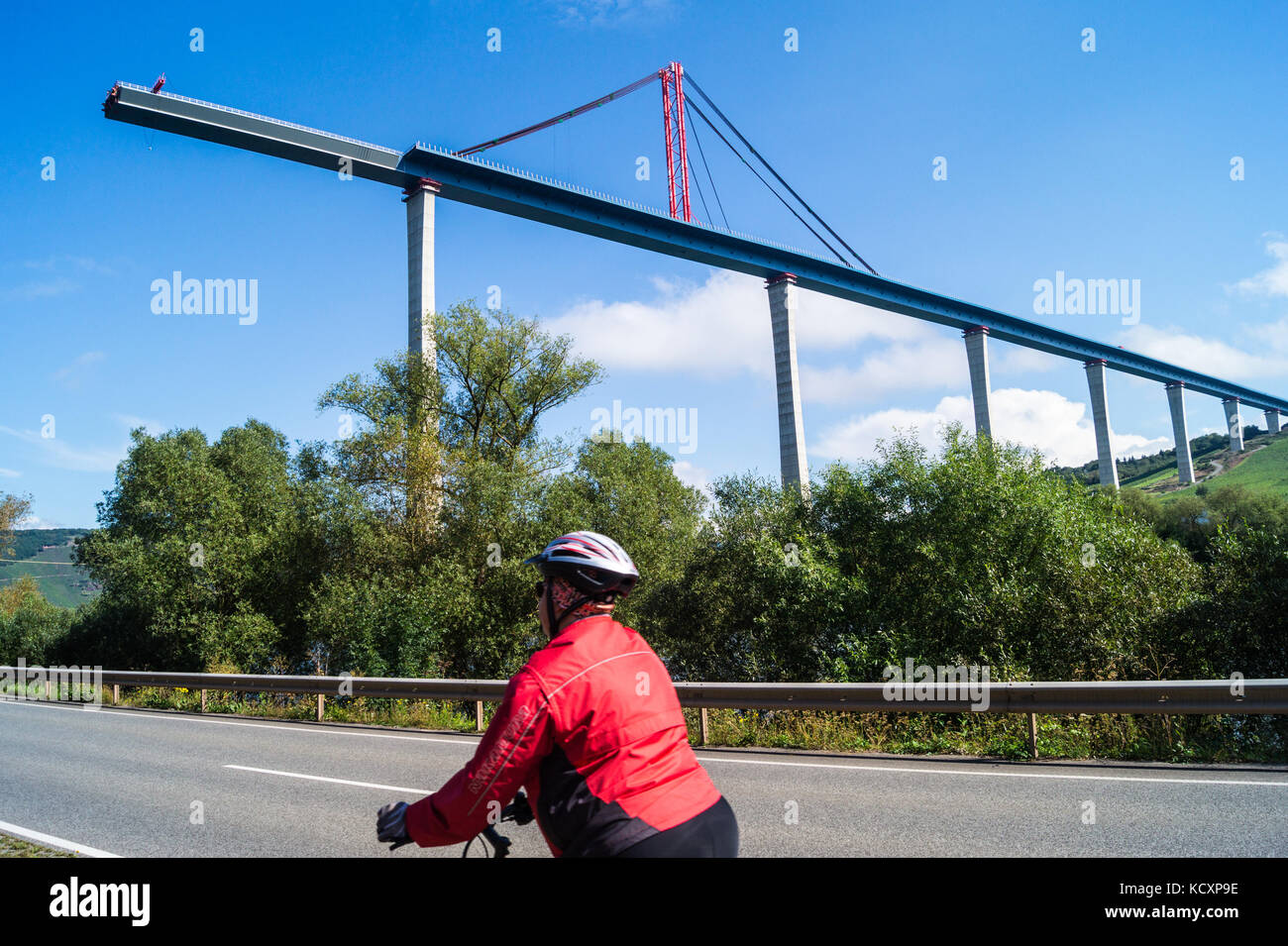 A female cyclist looking at the Hochmoselübergang B50 motorway bridge ...