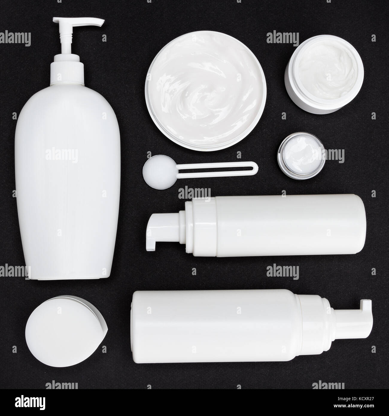 White cosmetic containers on black surface. Different cosmetic products ...