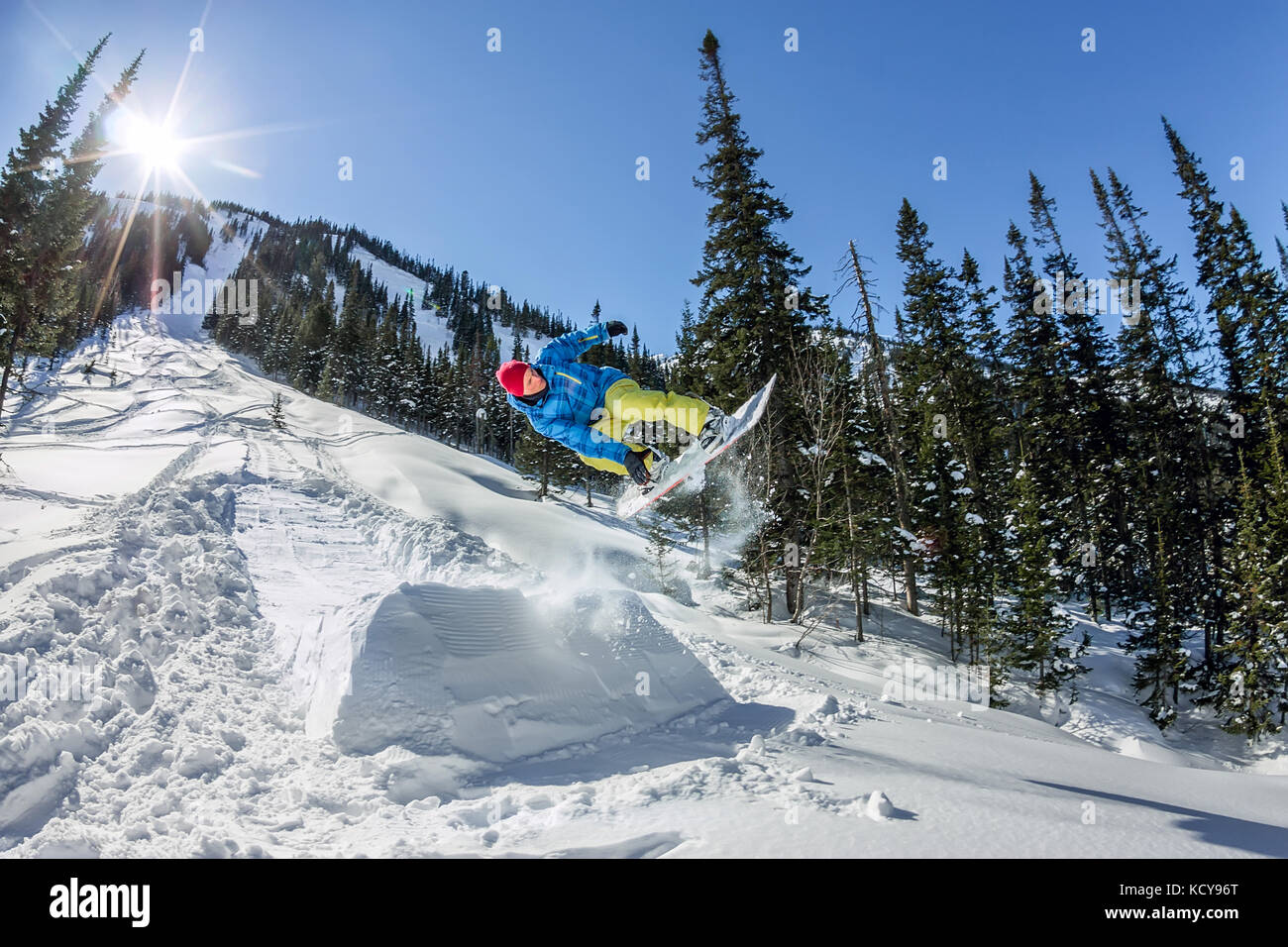 Snowboarder freerider jumping from a snow ramp in the sun on a ...