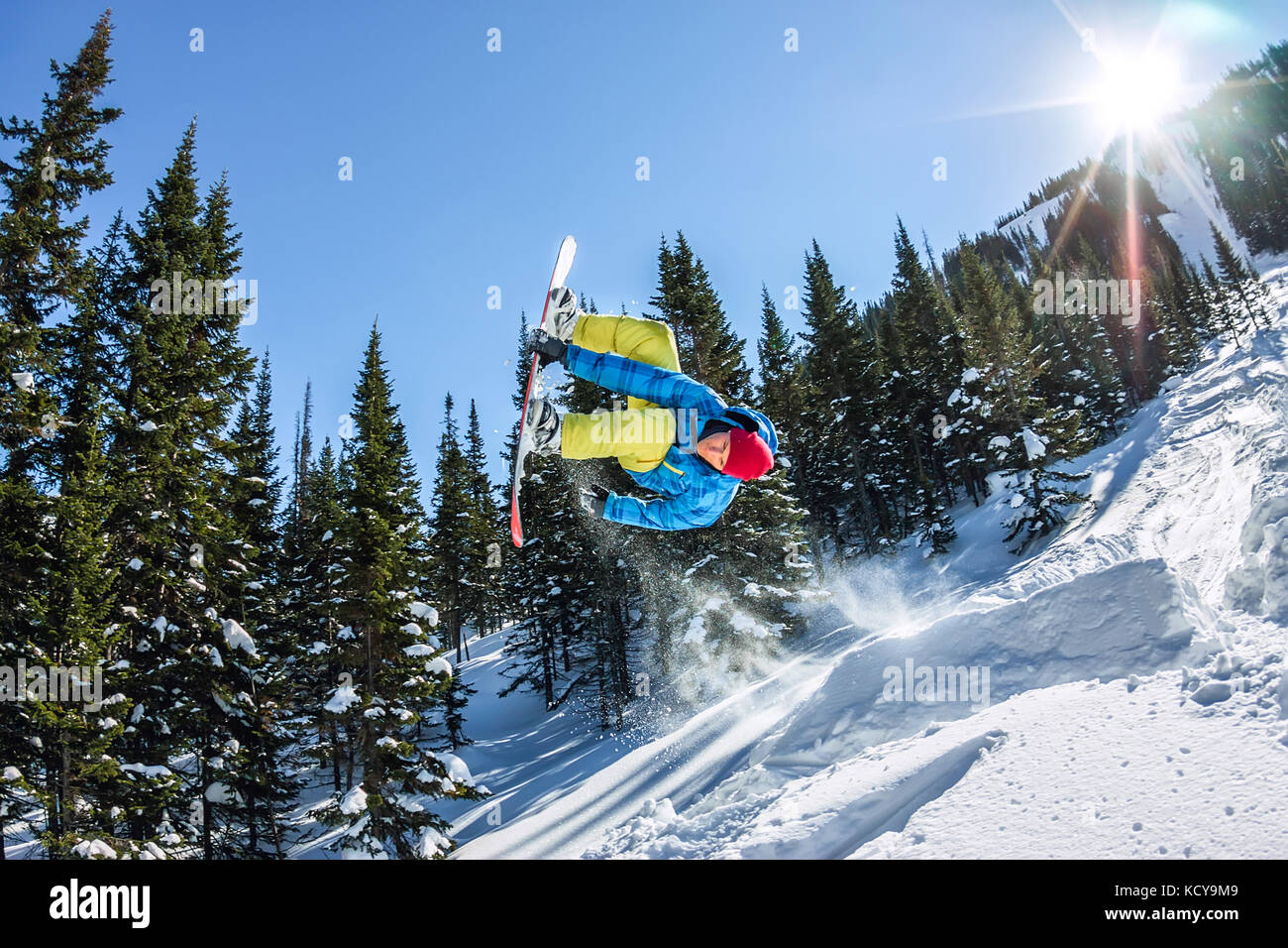 Snowboarder freerider jumping from a snow ramp in the sun on a ...