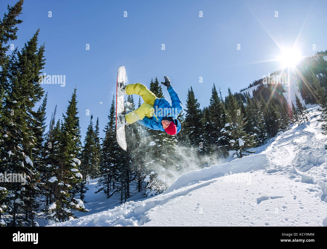 Snowboarder freerider jumping from a snow ramp in the sun on a ...