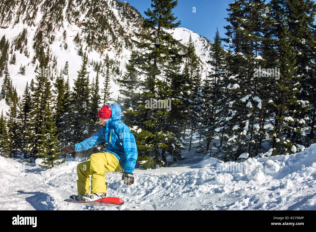 Snowboarder freerider jumping from a snow ramp in the sun on a ...