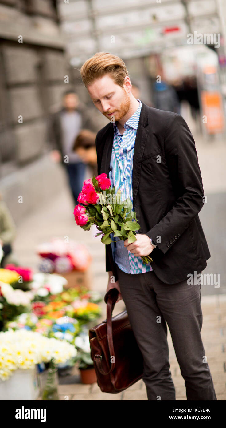 Man standing with a bouquet of roses on the street Stock Photo - Alamy