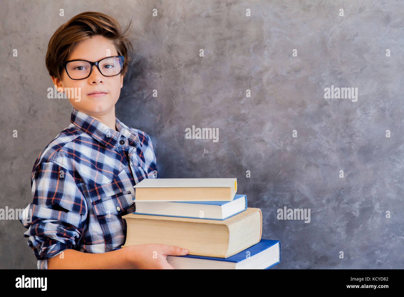 Cute teenage school boy holding books against wall Stock Photo - Alamy
