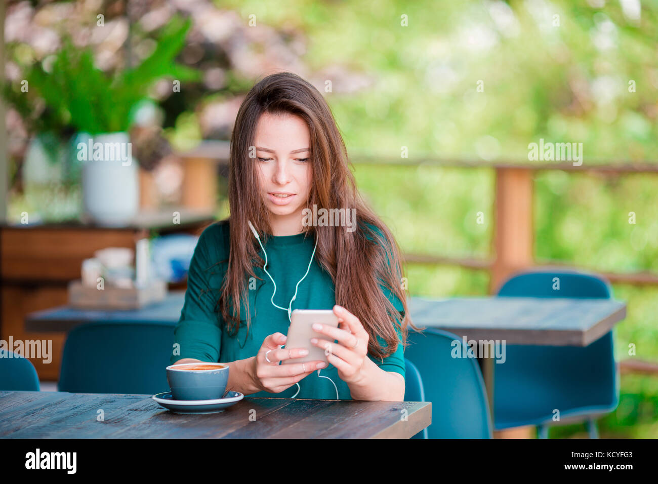 Young charming woman calling with cell telephone while sitting alone in ...