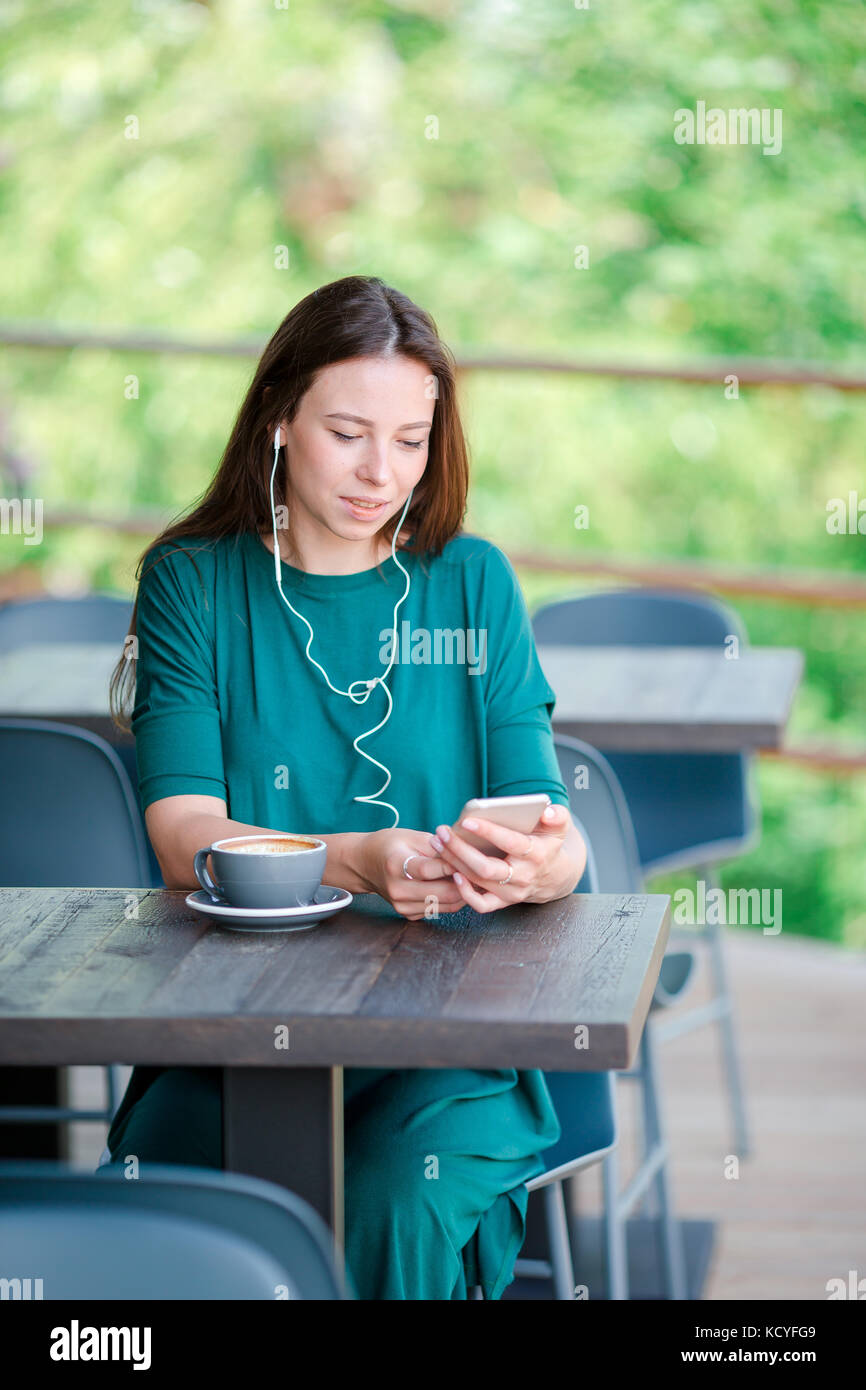 Young charming woman calling with cell telephone while sitting alone in ...