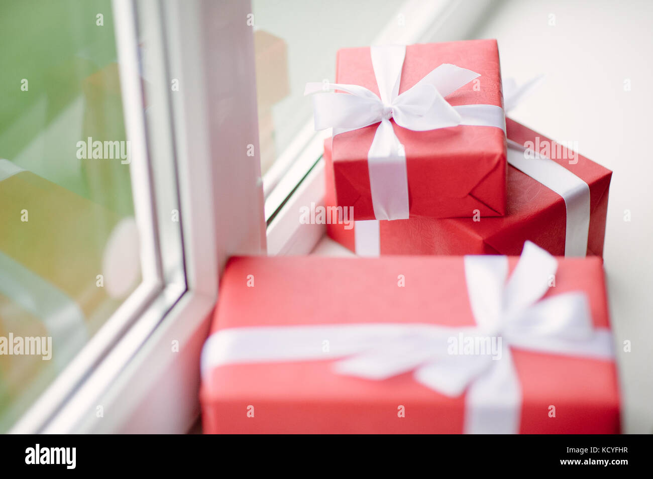three red boxes with gifts tied with a white ribbon near the window ...