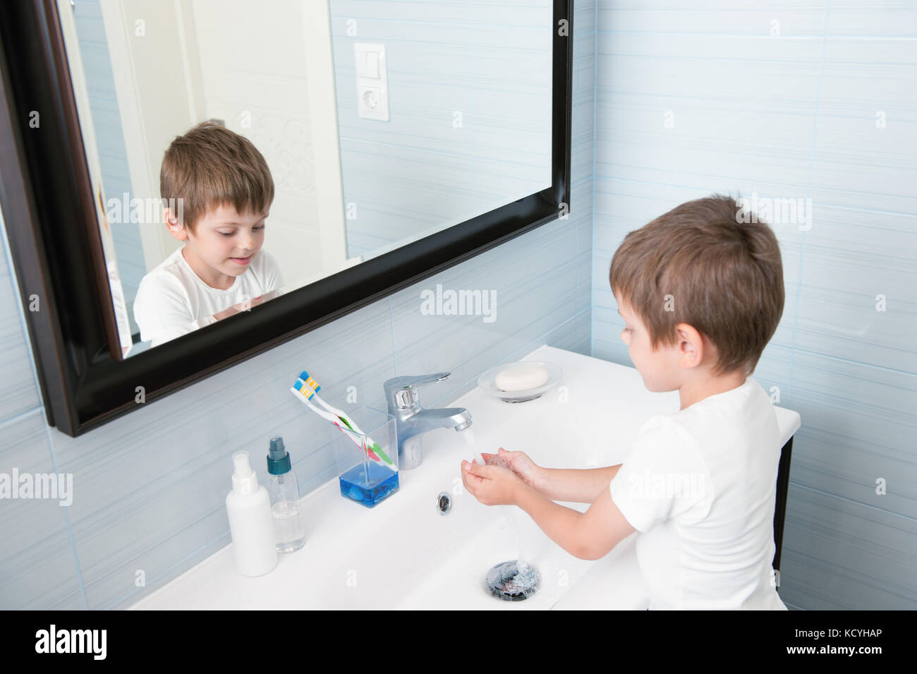 beautiful little boy washes his hands in blue bathroom Stock Photo - Alamy