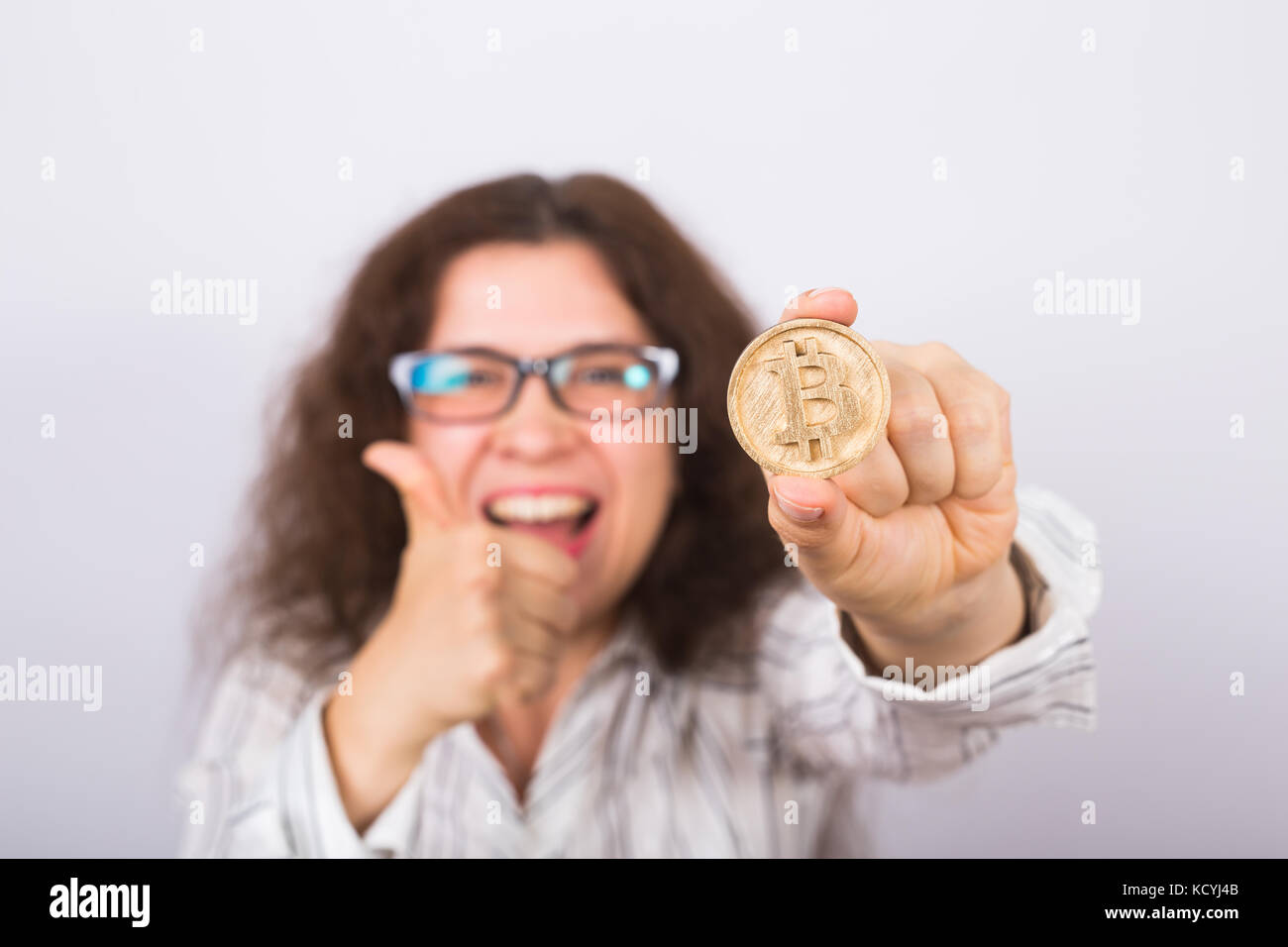 Laughing business woman showing Golden Bitcoin coin and thumbs up ...