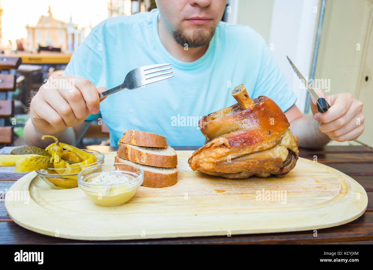 man eating knuckle of pork and drinks beer close-up Stock Photo - Alamy